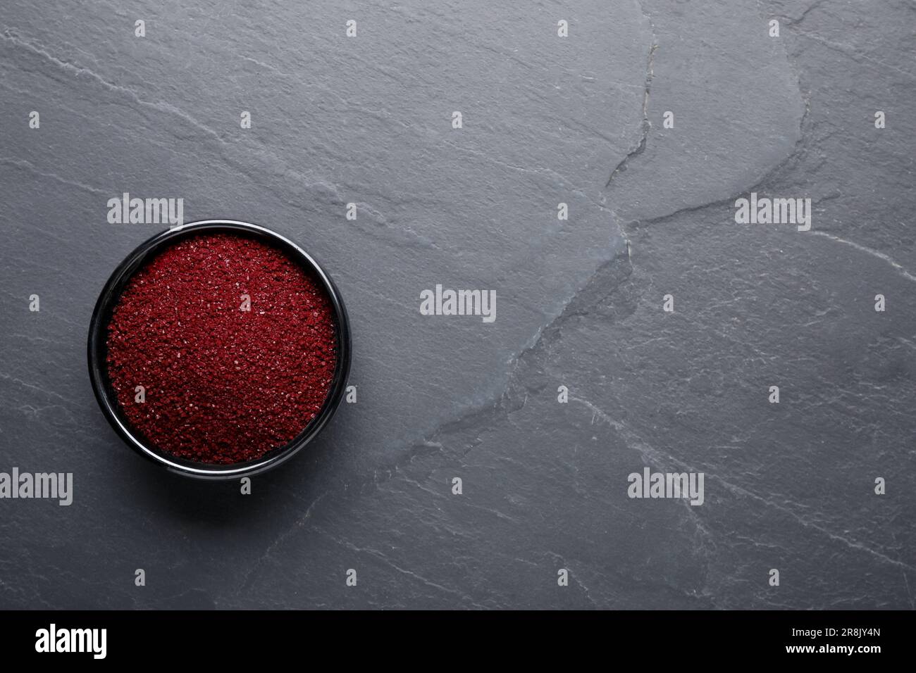 Bowl of dark red food coloring on grey table, top view. Space for text ...