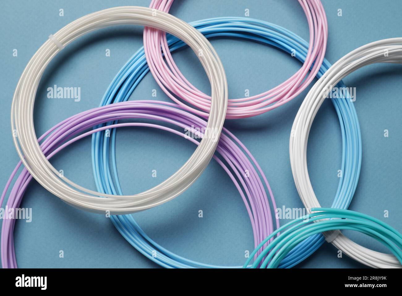 Colorful plastic filaments for 3D pen on light blue background, flat ...
