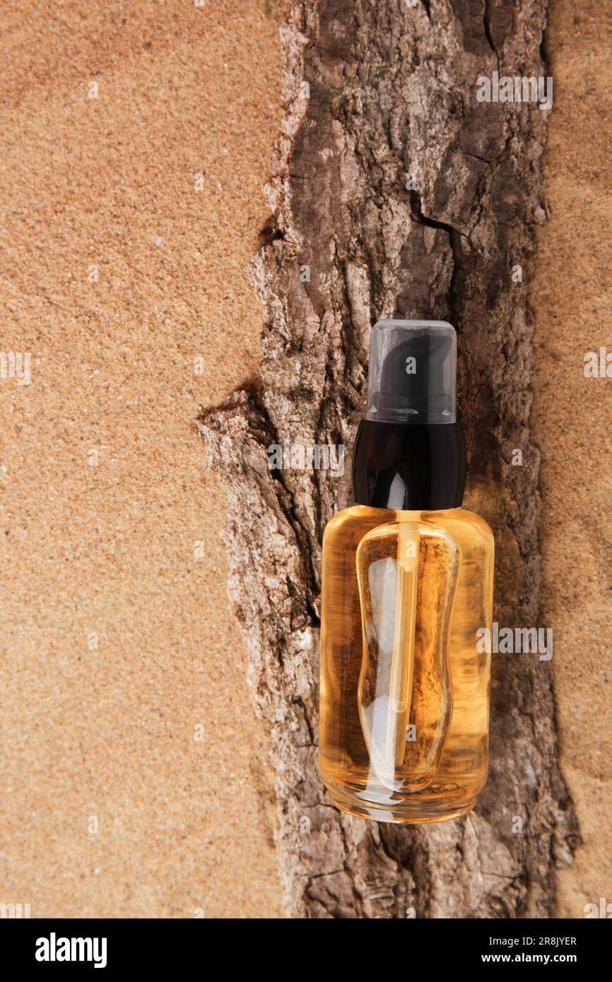 Bottle of serum and tree bark on sand, top view Stock Photo - Alamy