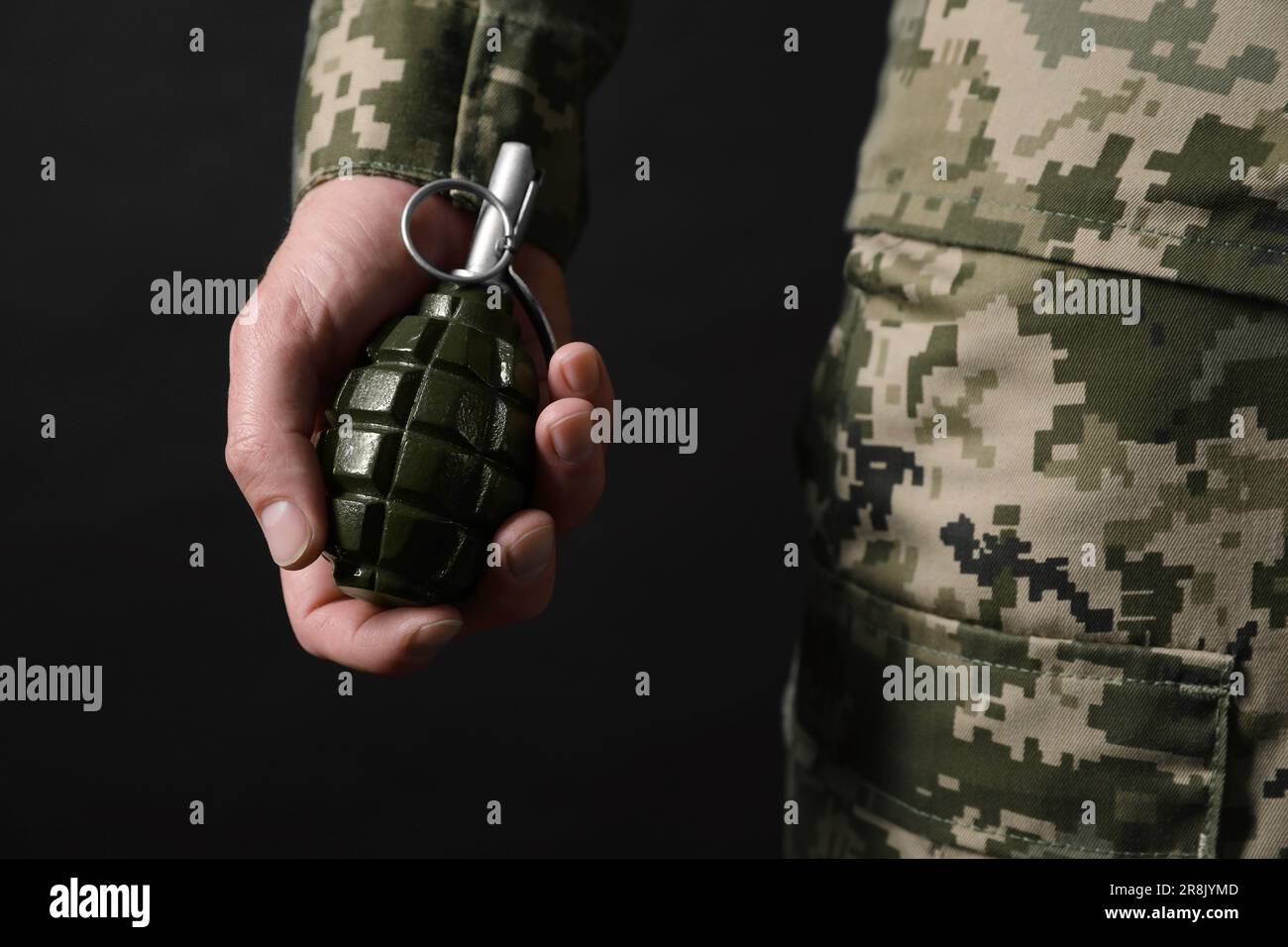 Soldier holding hand grenade on black background, closeup. Military ...