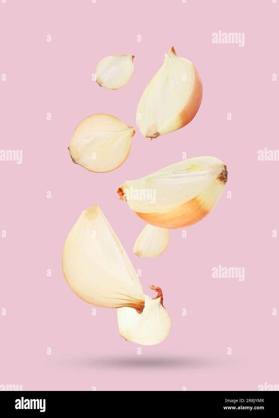 Cut fresh onions falling on pastel pink background Stock Photo - Alamy