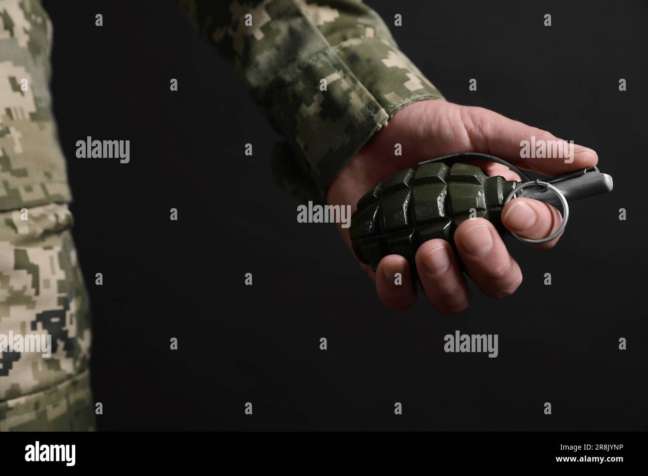 Soldier holding hand grenade on black background, closeup. Military ...