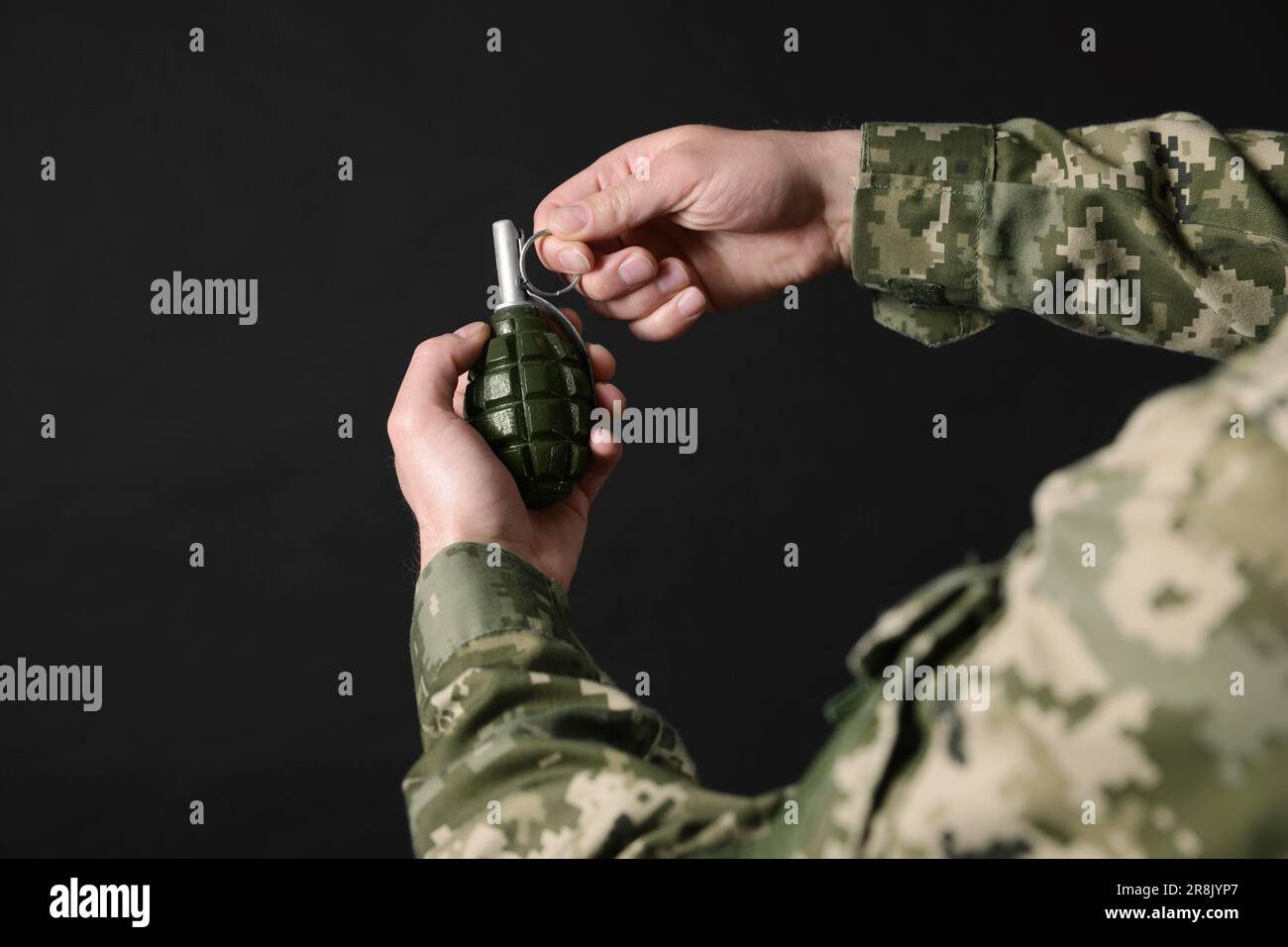 Soldier pulling safety pin out of hand grenade on black background ...