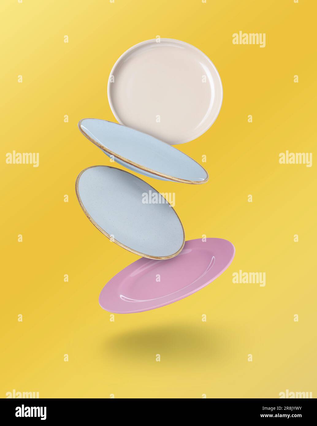 Many different plates falling on yellow gradient background Stock Photo ...