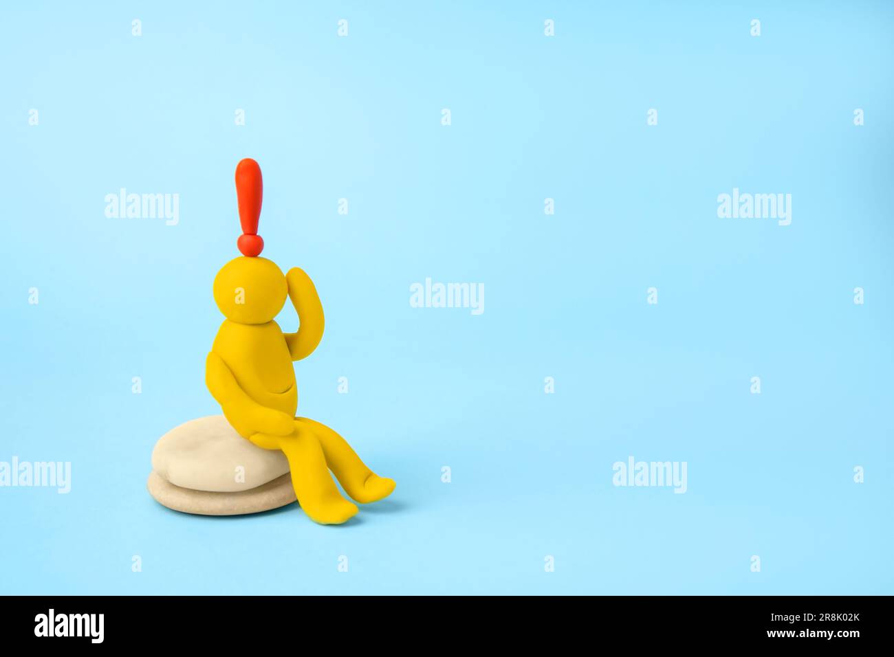 Human figure made of yellow plasticine with exclamation mark as solution idea on light blue ...