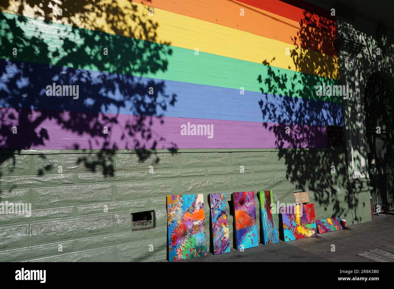 A building painted in the pride flag colors with art pieces resting on ...