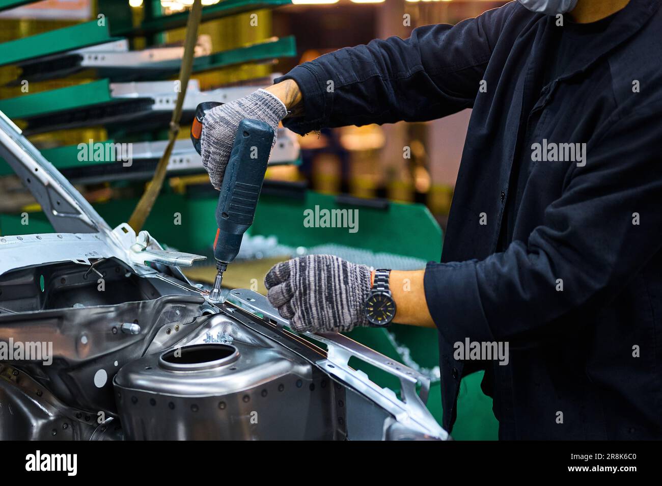 Worker prepares to screw car body parts on workshop conveyor Stock ...