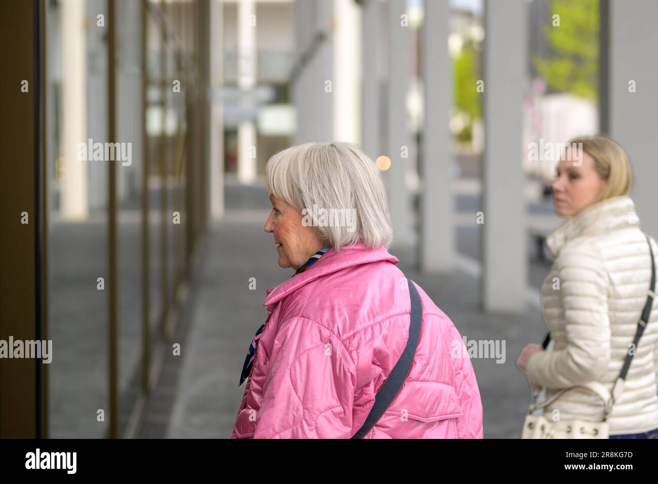 Back view of a mother and daughter walking and looking into a shopping ...