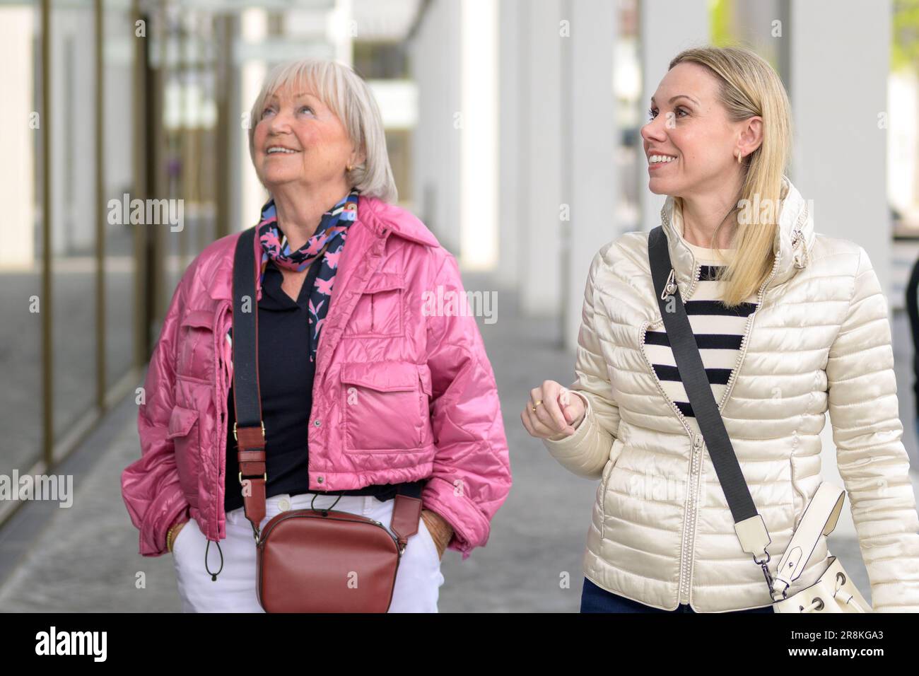 Mother and daughter standing and looking to a shop window while ...