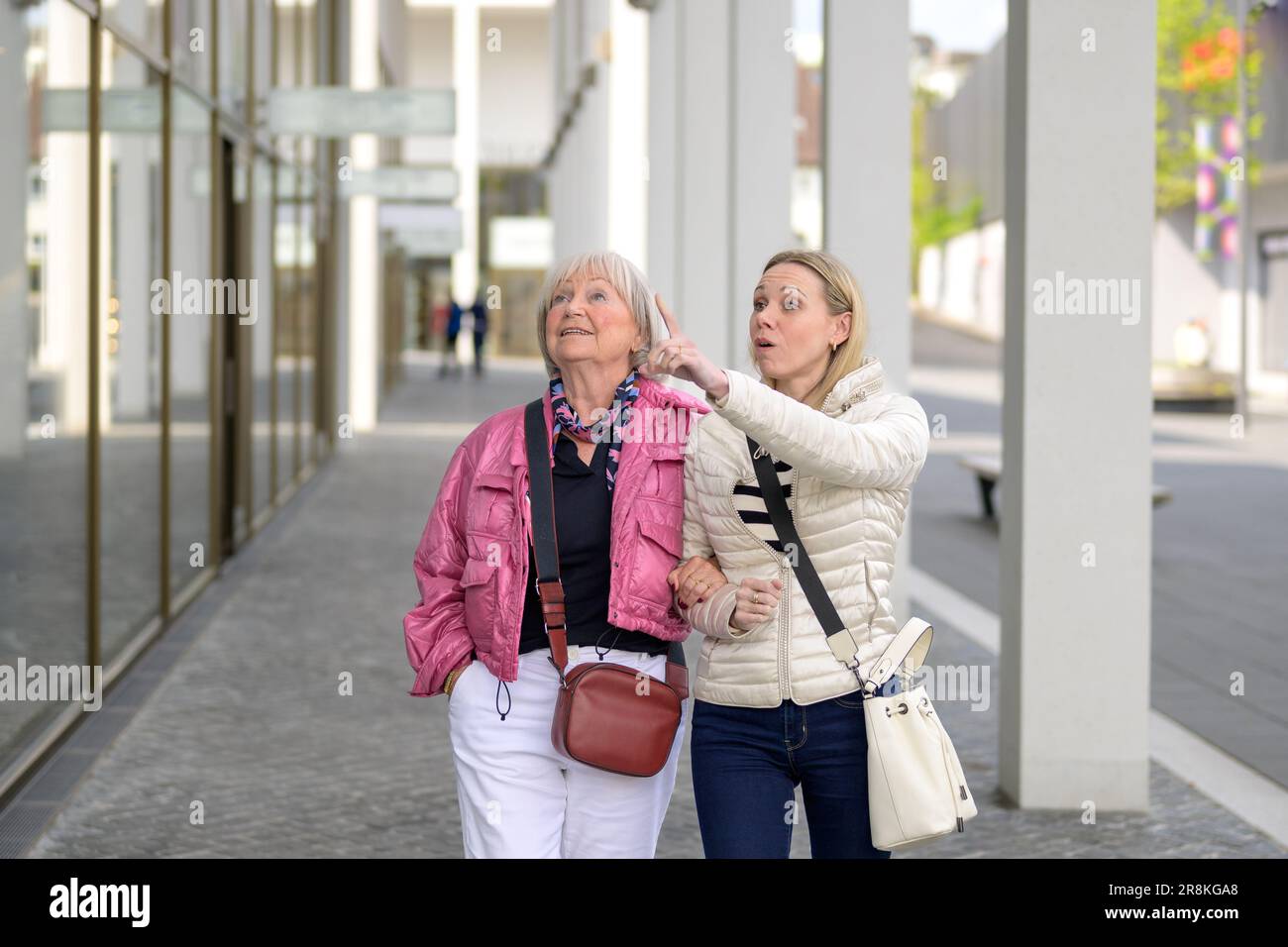 Mother and daughter shopping in a mall and the daughter is pointing to ...