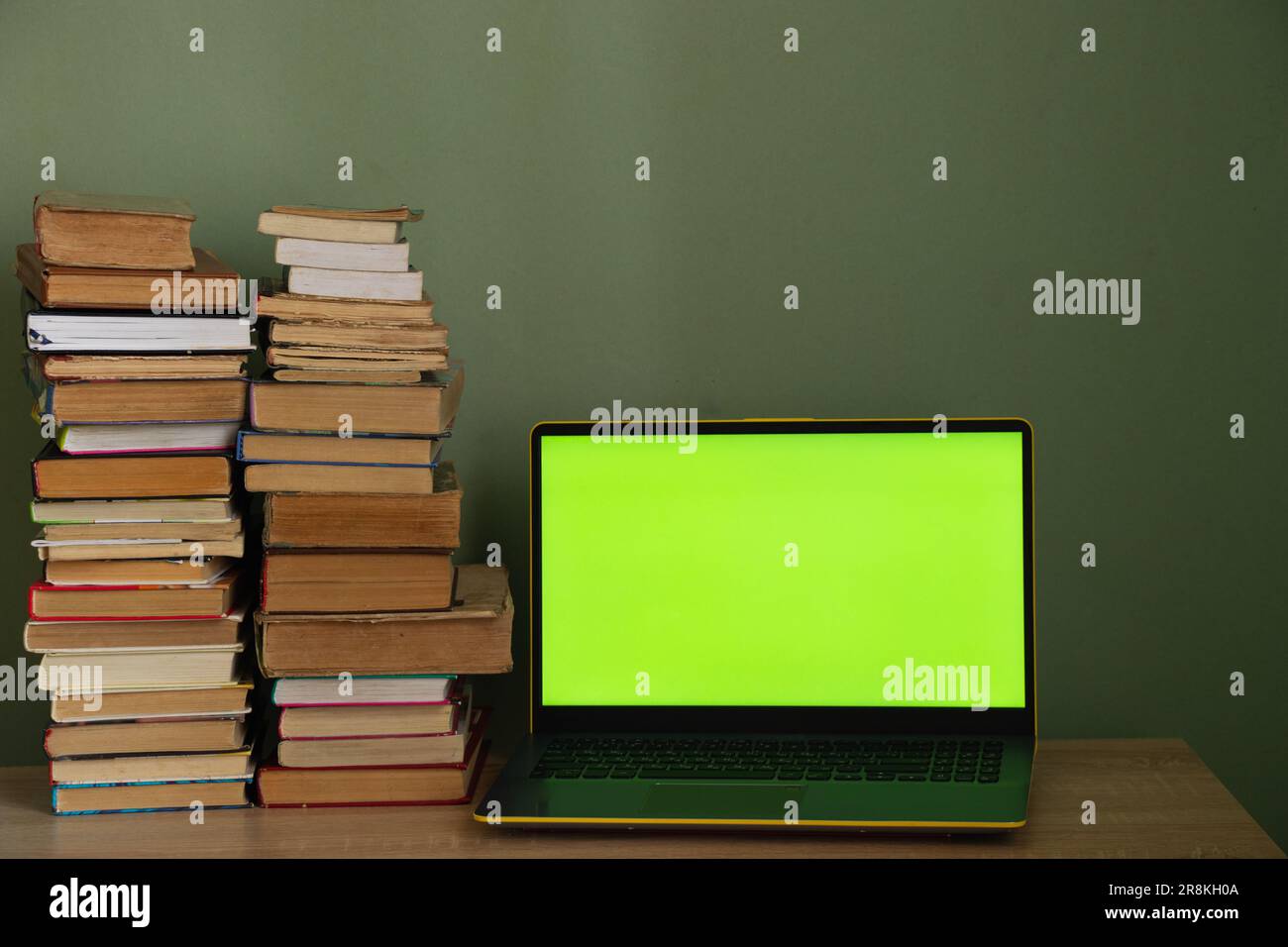 laptop green screen and a stack of books on the table Stock Photo - Alamy