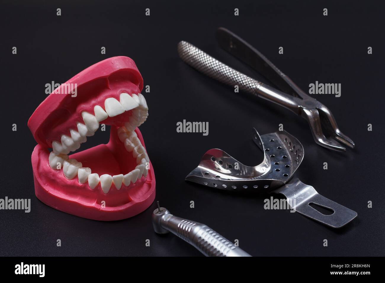 Stainless steel dental tools and layout of a human jaw on the black ...
