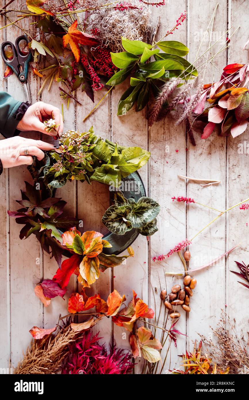 An adult cutting fresh flowers from a traditional wreath made of ...