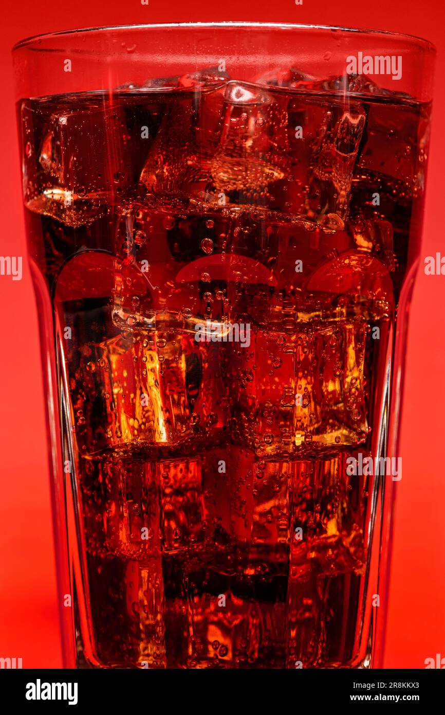 Glass full of ice cubes and a fresh cold cola over red background Stock ...