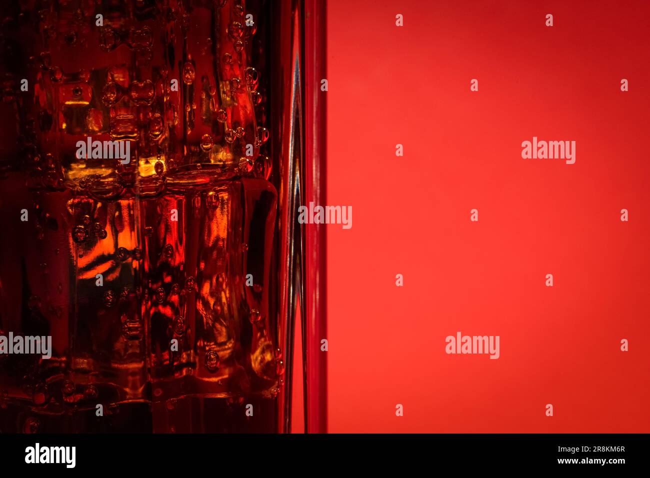 Glass full of ice cubes and a fresh cold cola over red background with ...