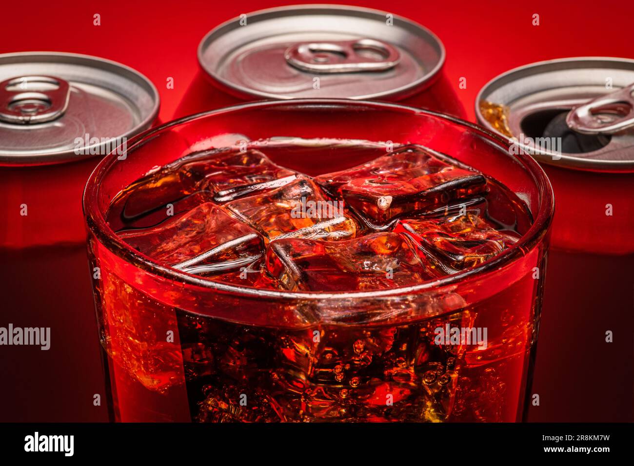 Glass full of ice cubes and a fresh cold cola over red background Stock ...