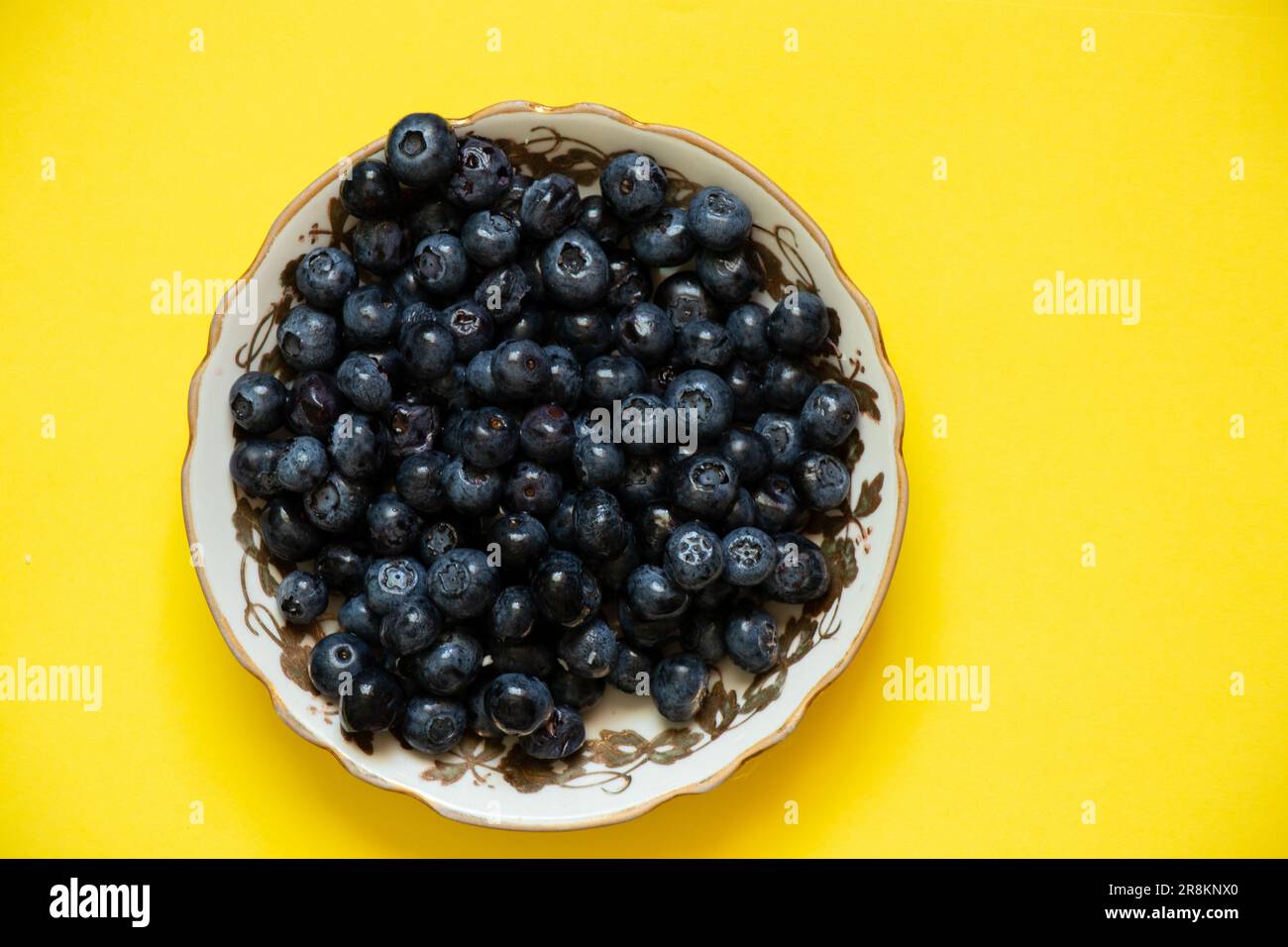 blueberries on a table in a plate close-up on a yellow background Stock ...