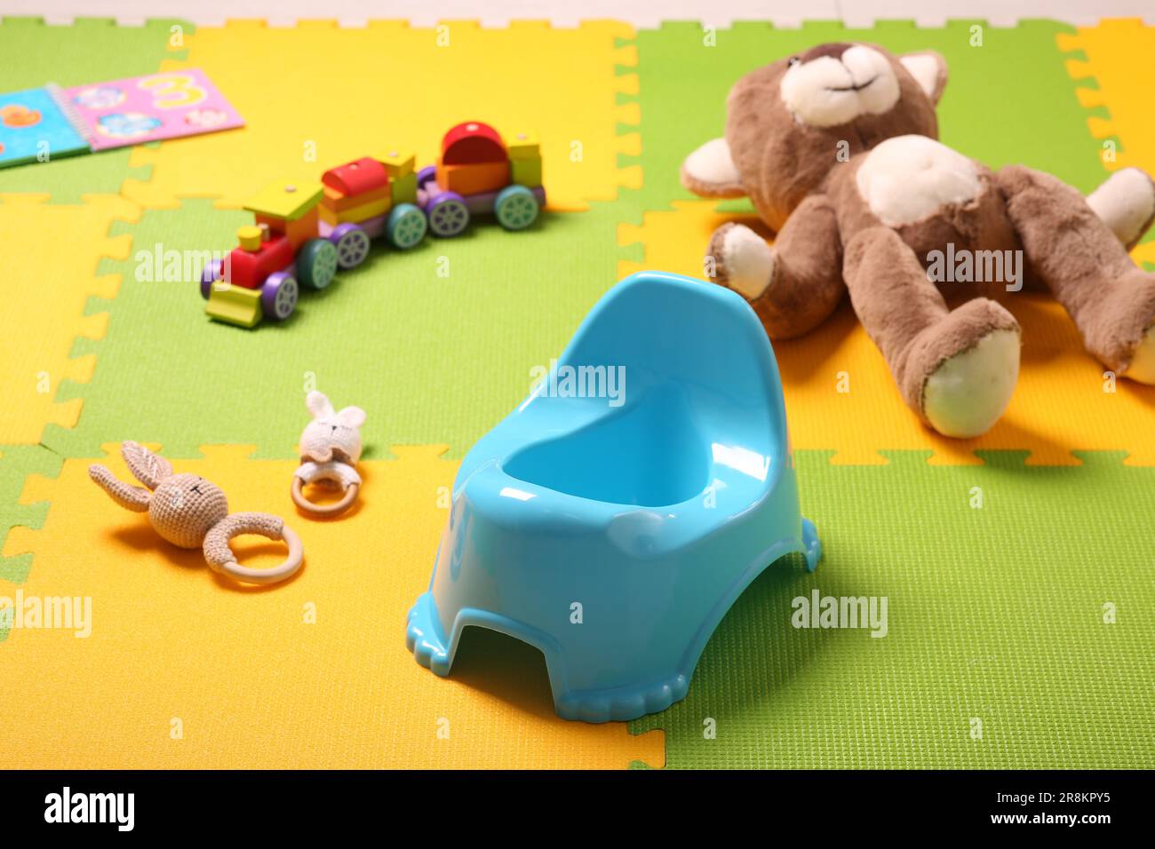 Light blue baby potty and toys on colorful puzzle mat. Toilet training ...