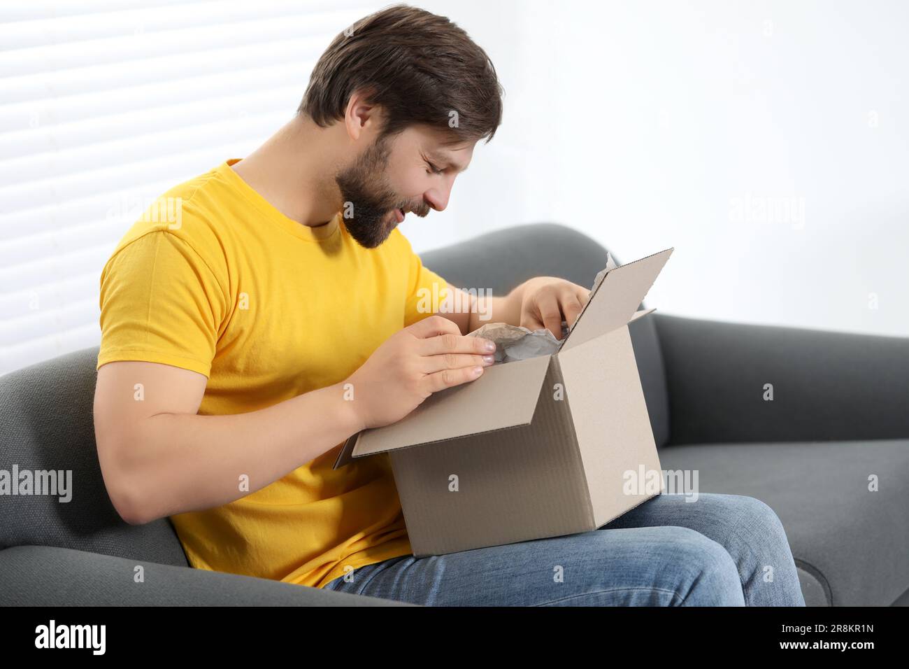 Happy man opening parcel at home. Internet shopping Stock Photo - Alamy