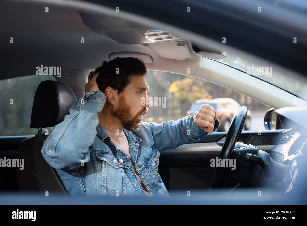 Emotional man checking time on watch in car. Being late concept Stock ...