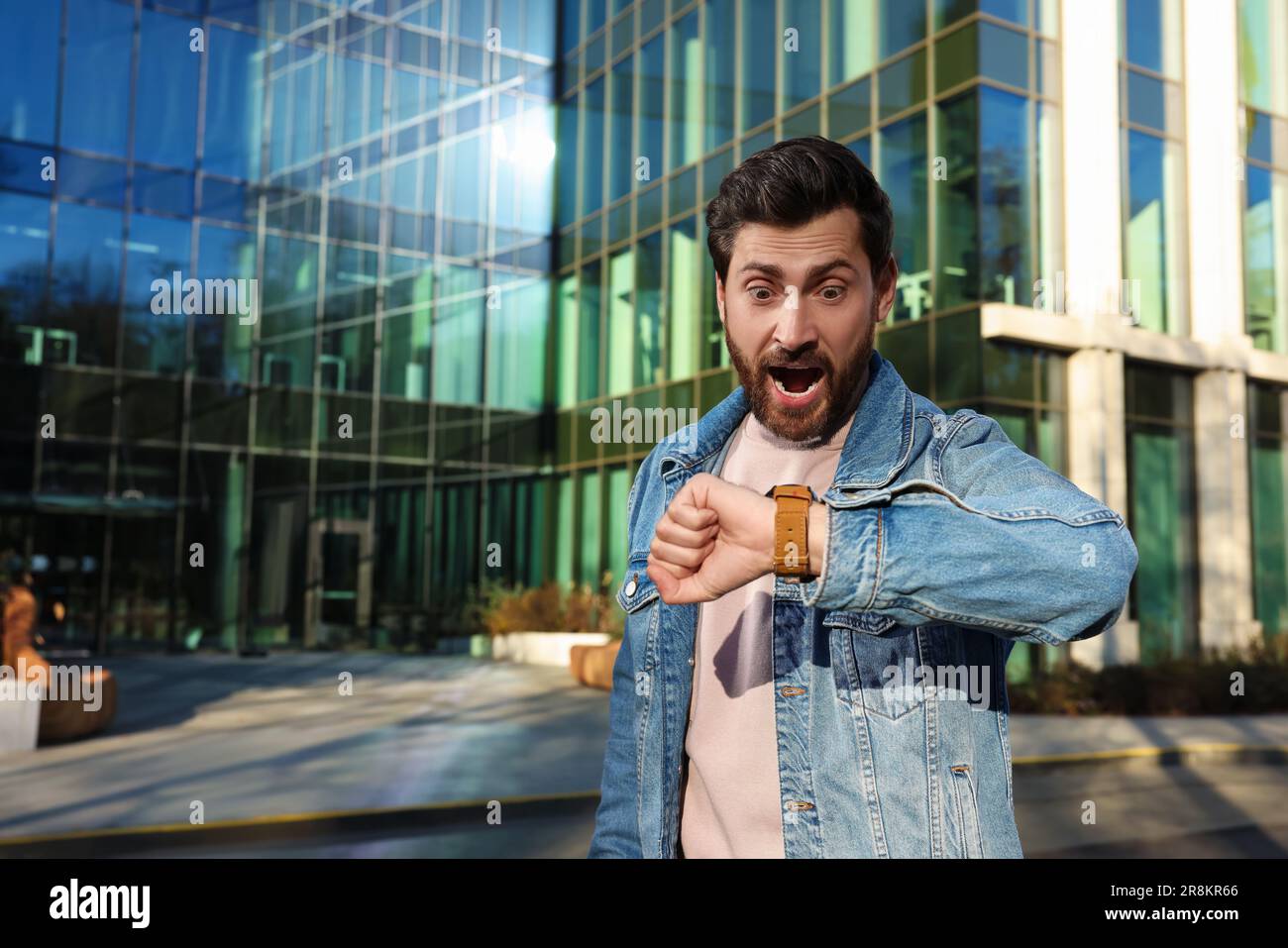 Emotional man checking time on watch near building. Being late concept ...