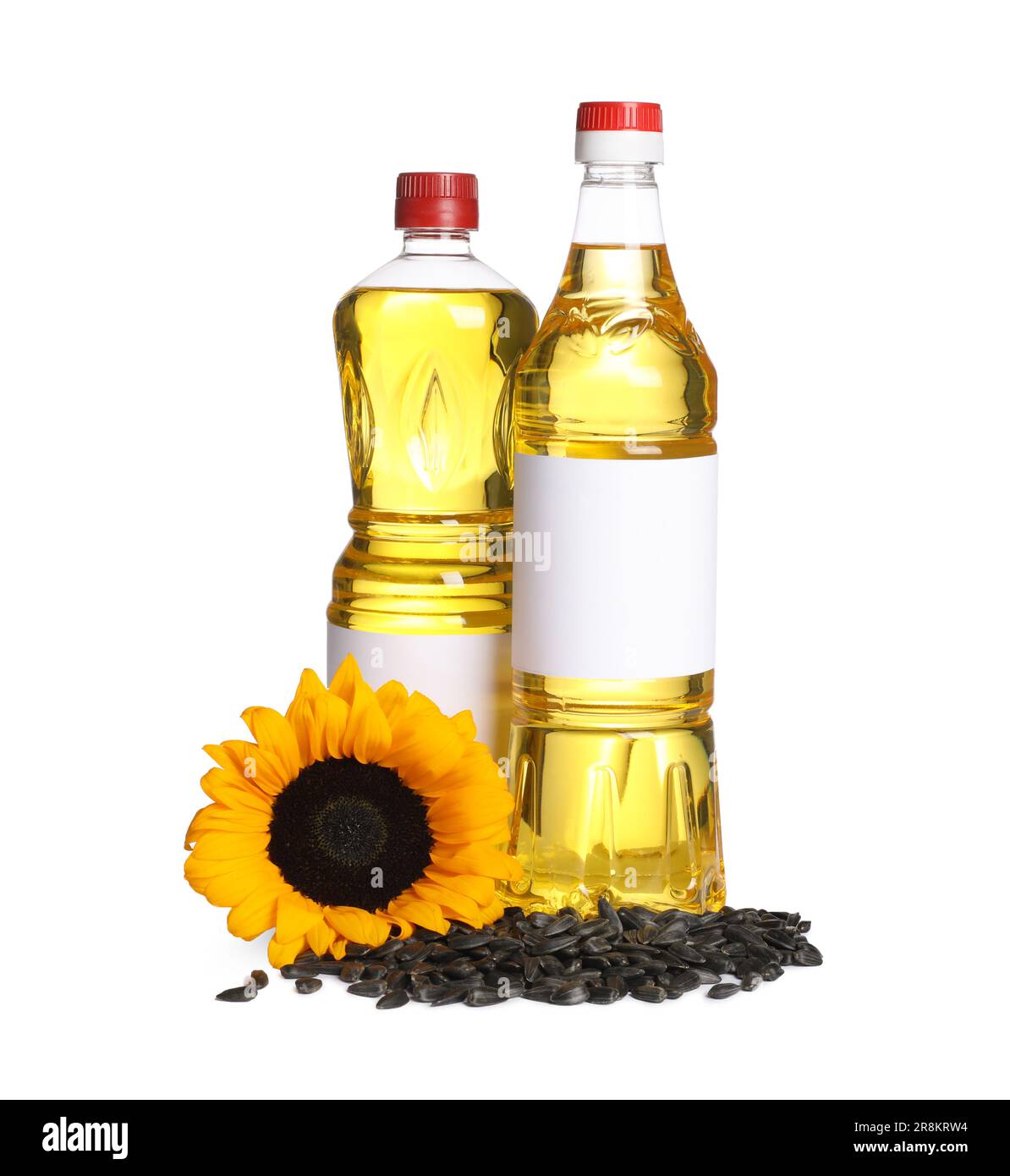Bottles of sunflower cooking oil, seeds and yellow flower on white ...
