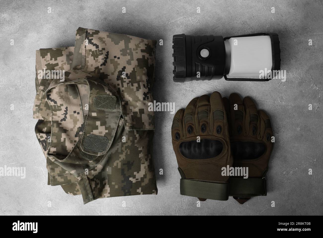 Tactical gloves, camouflage jacket and camping lantern on light gray ...