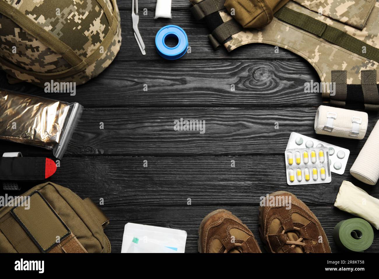 Frame of military first aid kit and uniform on wooden table, flat lay ...