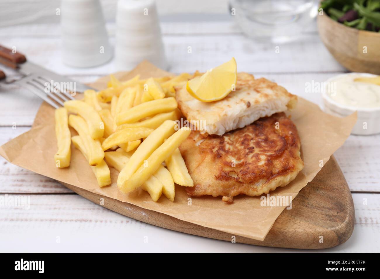 Tasty soda water battered fish, potato chips and lemon slice on white ...