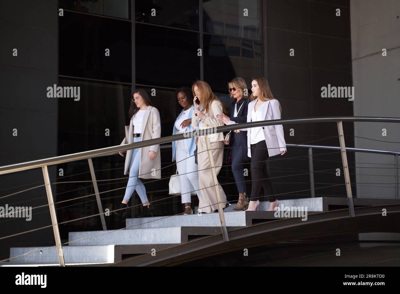 Successful female executives in formal attire walking out of office ...