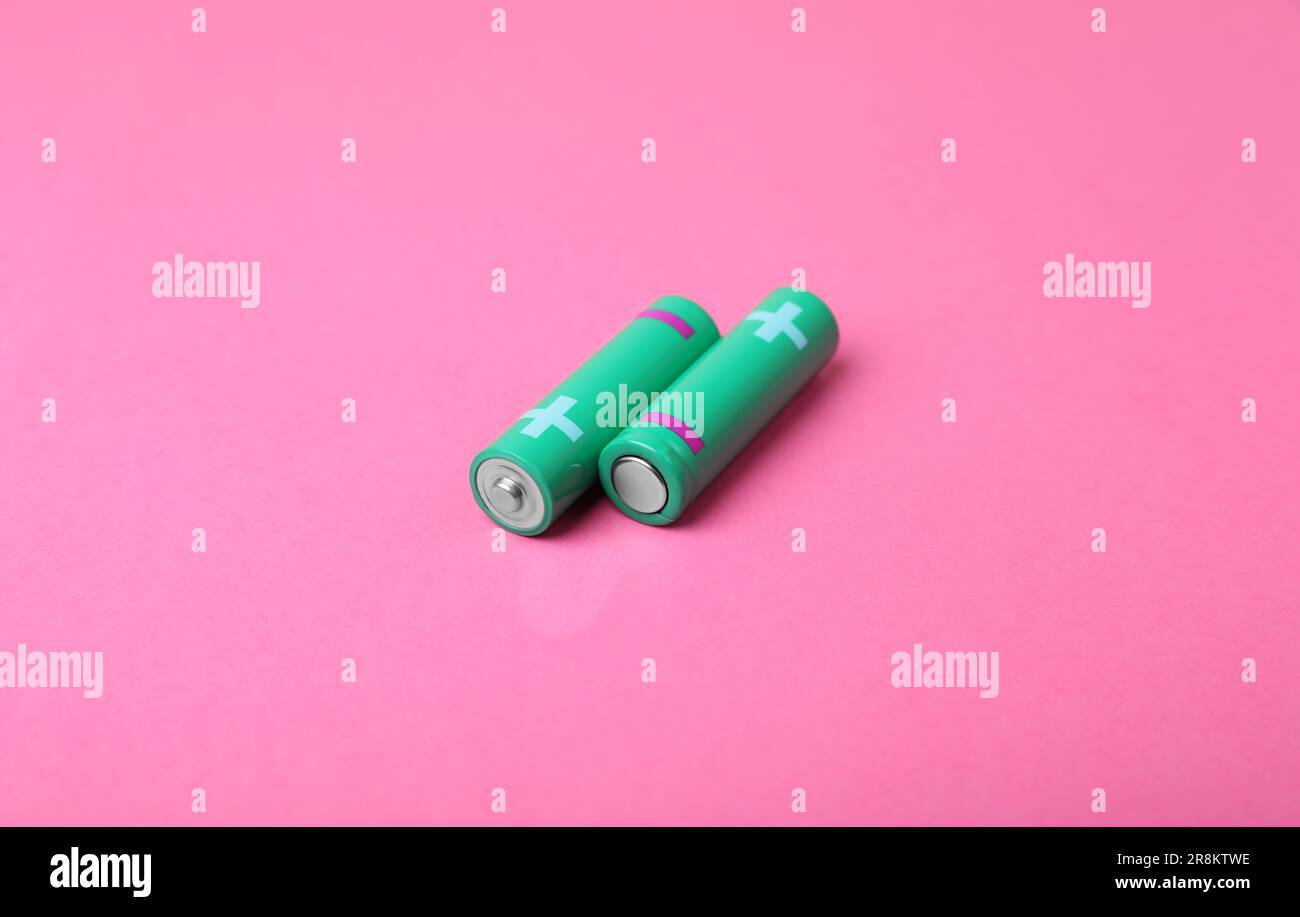 New AA size batteries on pink background Stock Photo - Alamy
