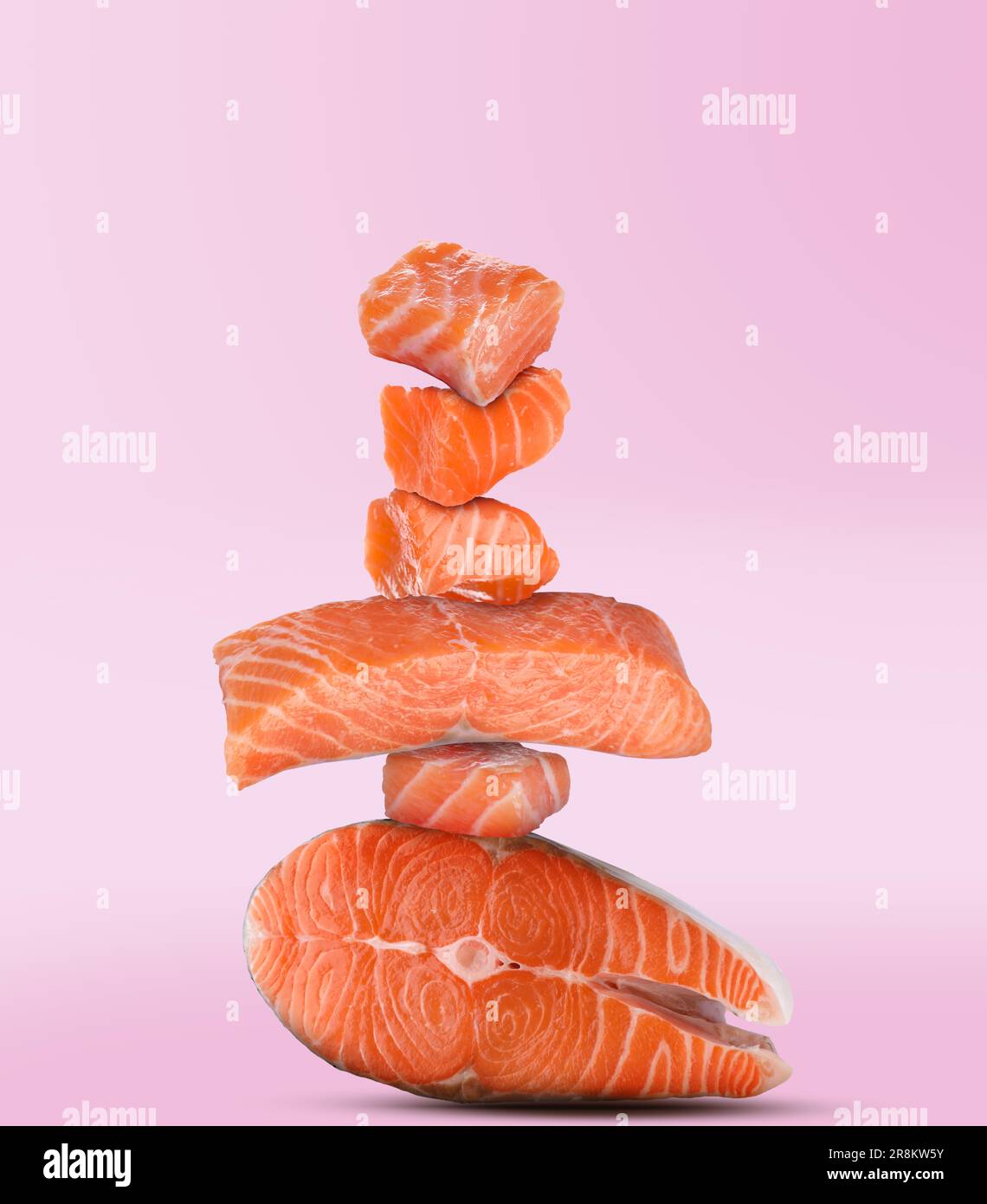 Cut fresh salmon falling on pink gradient background Stock Photo - Alamy