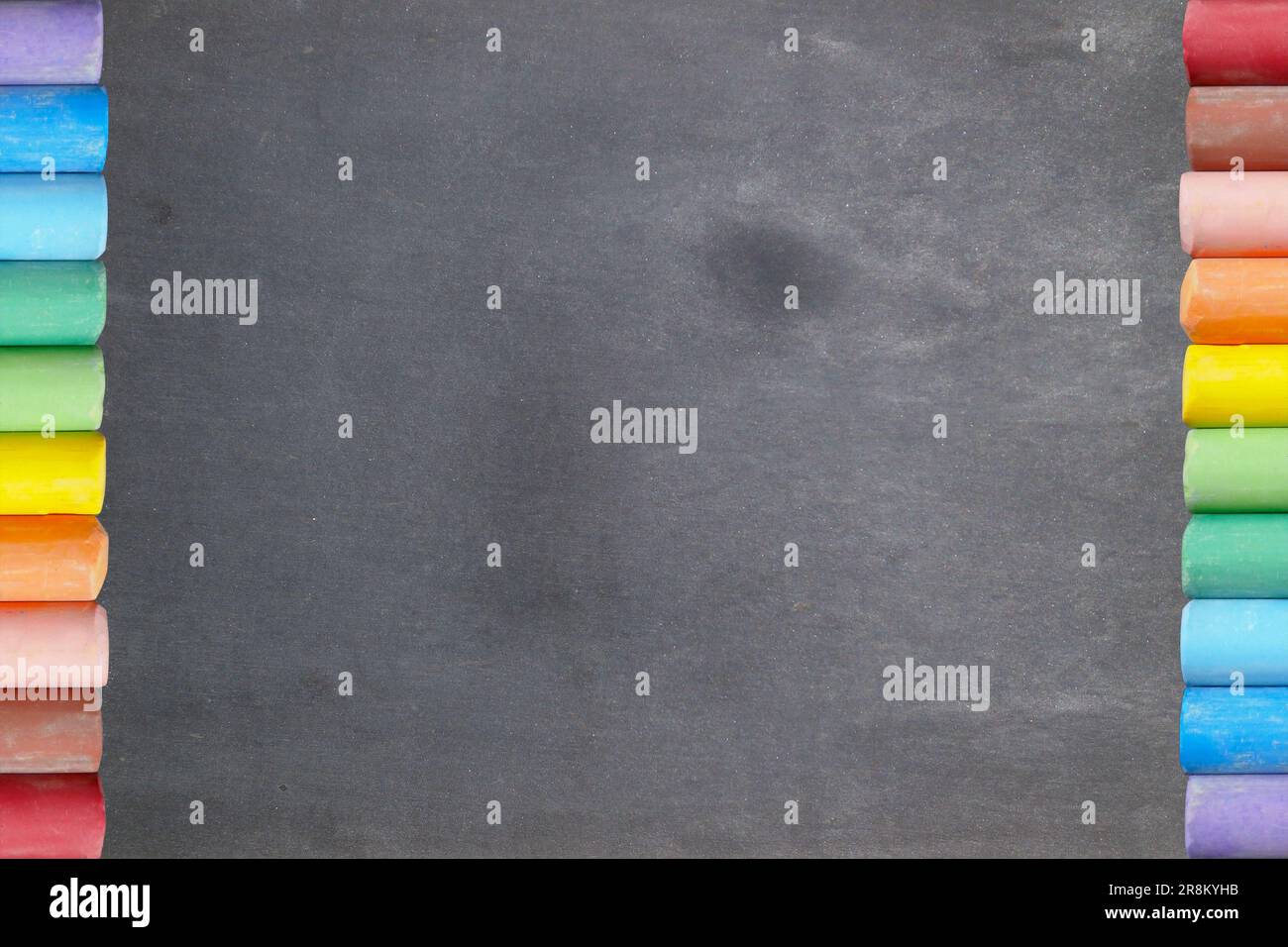 Two rows of colored chalks facing each other on a blank blackboard ...