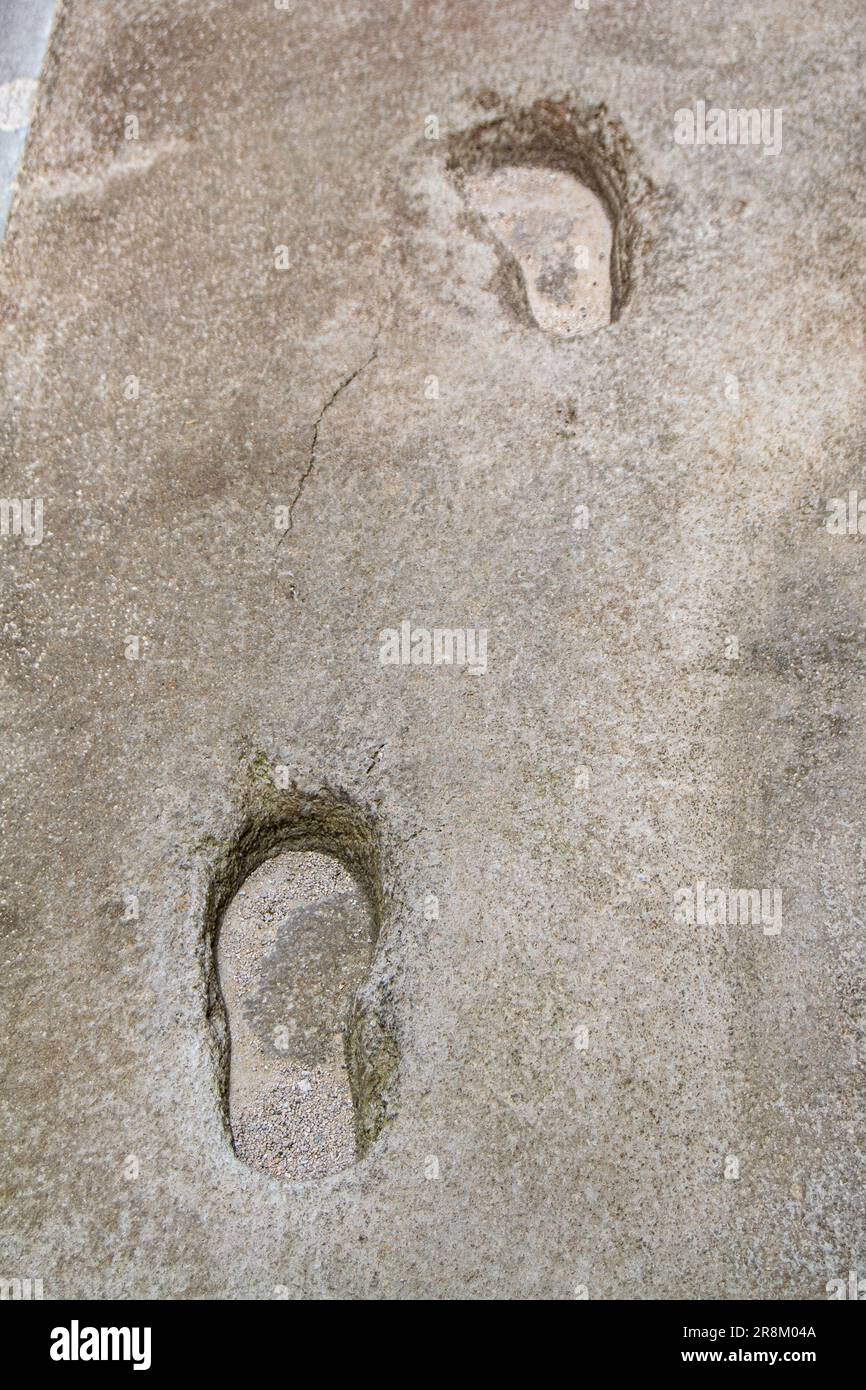 Deep footsteps on the concrete of a street floor Stock Photo - Alamy