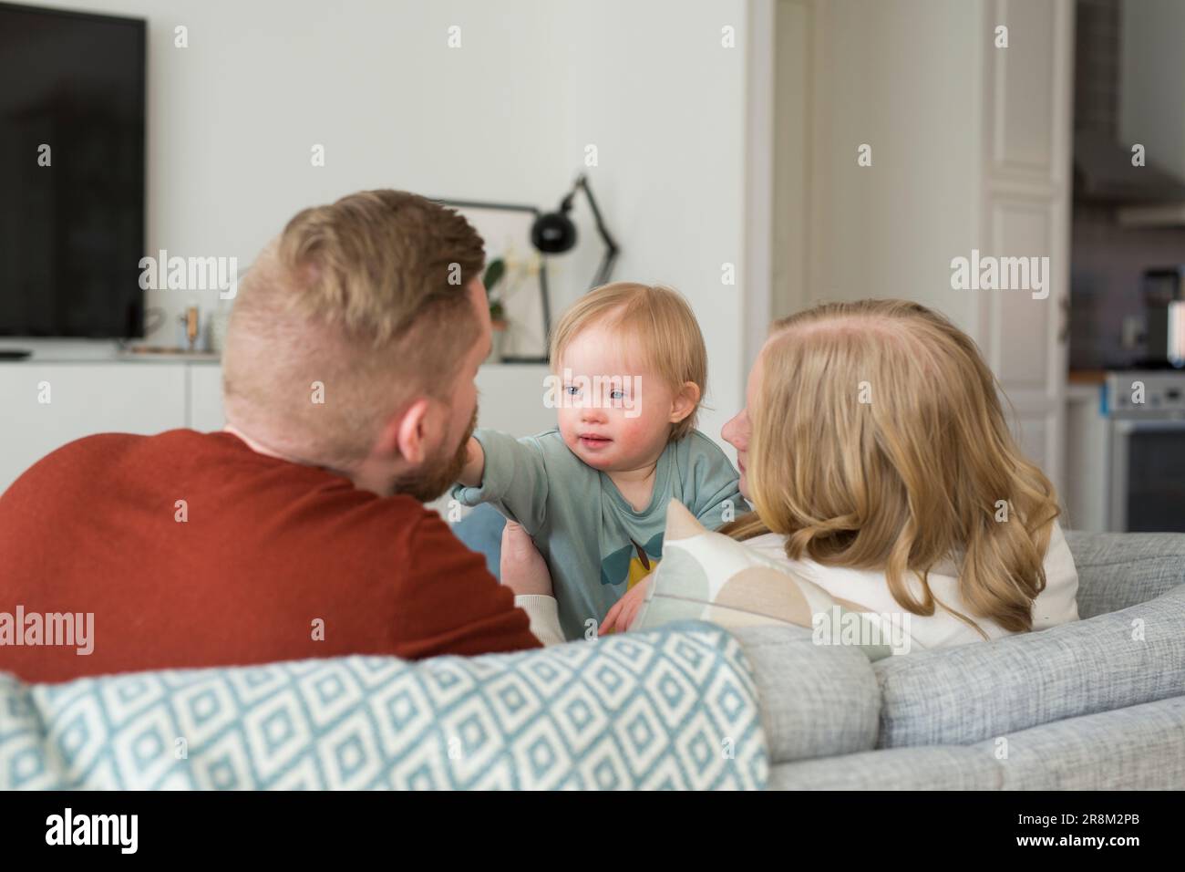 Parents playing with smiling baby Parents with baby with down syndrome ...