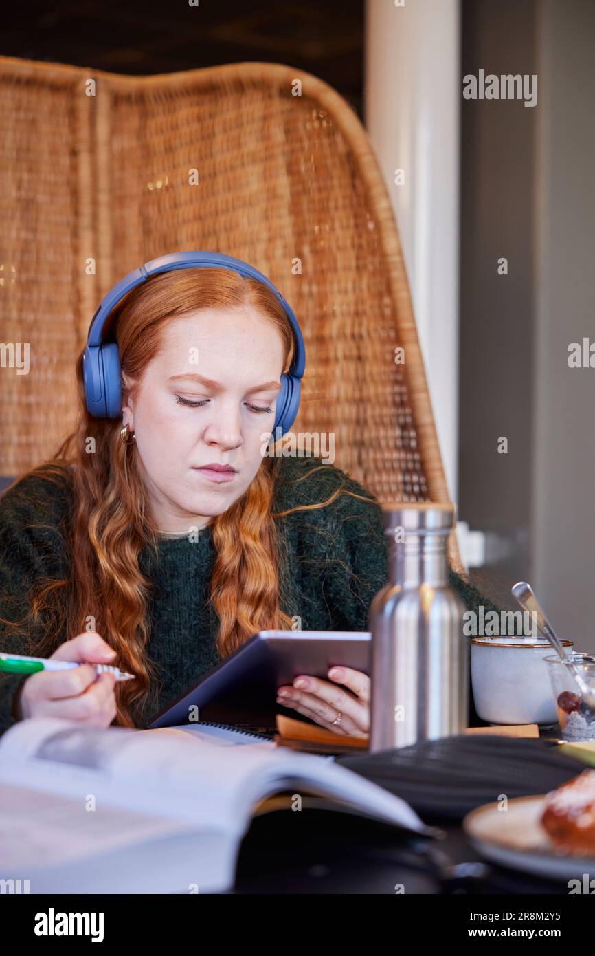 Young woman wearing headphones and studying Stock Photo - Alamy