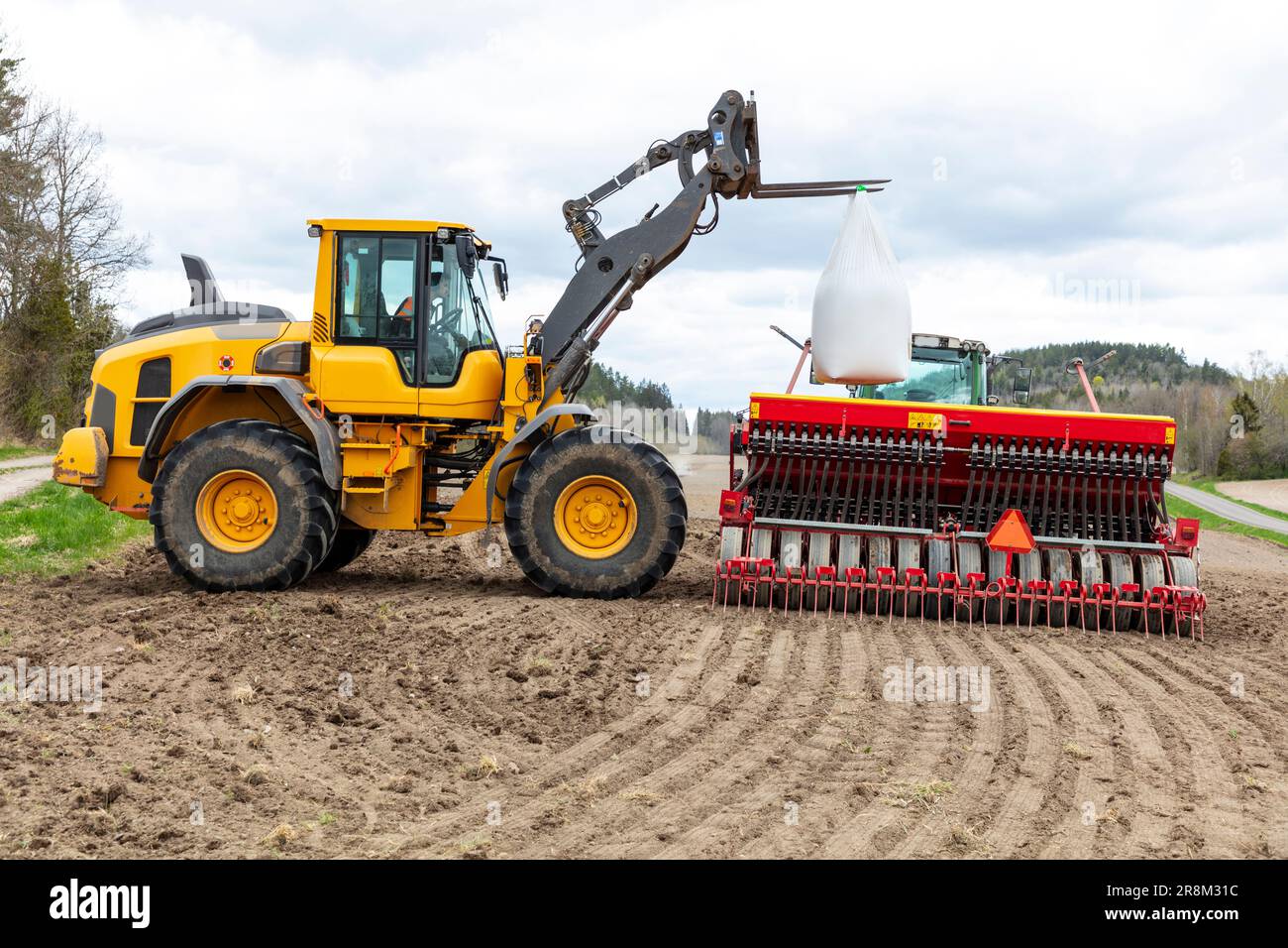 Farm machine working in plowed field Stock Photo - Alamy