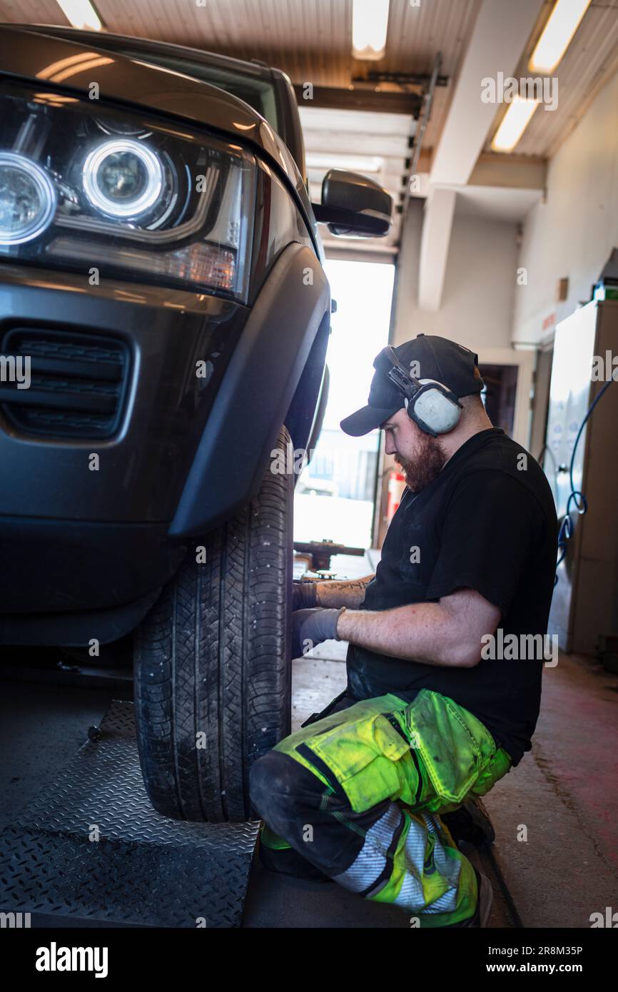 Mechanic in garage changing tires on car Stock Photo - Alamy