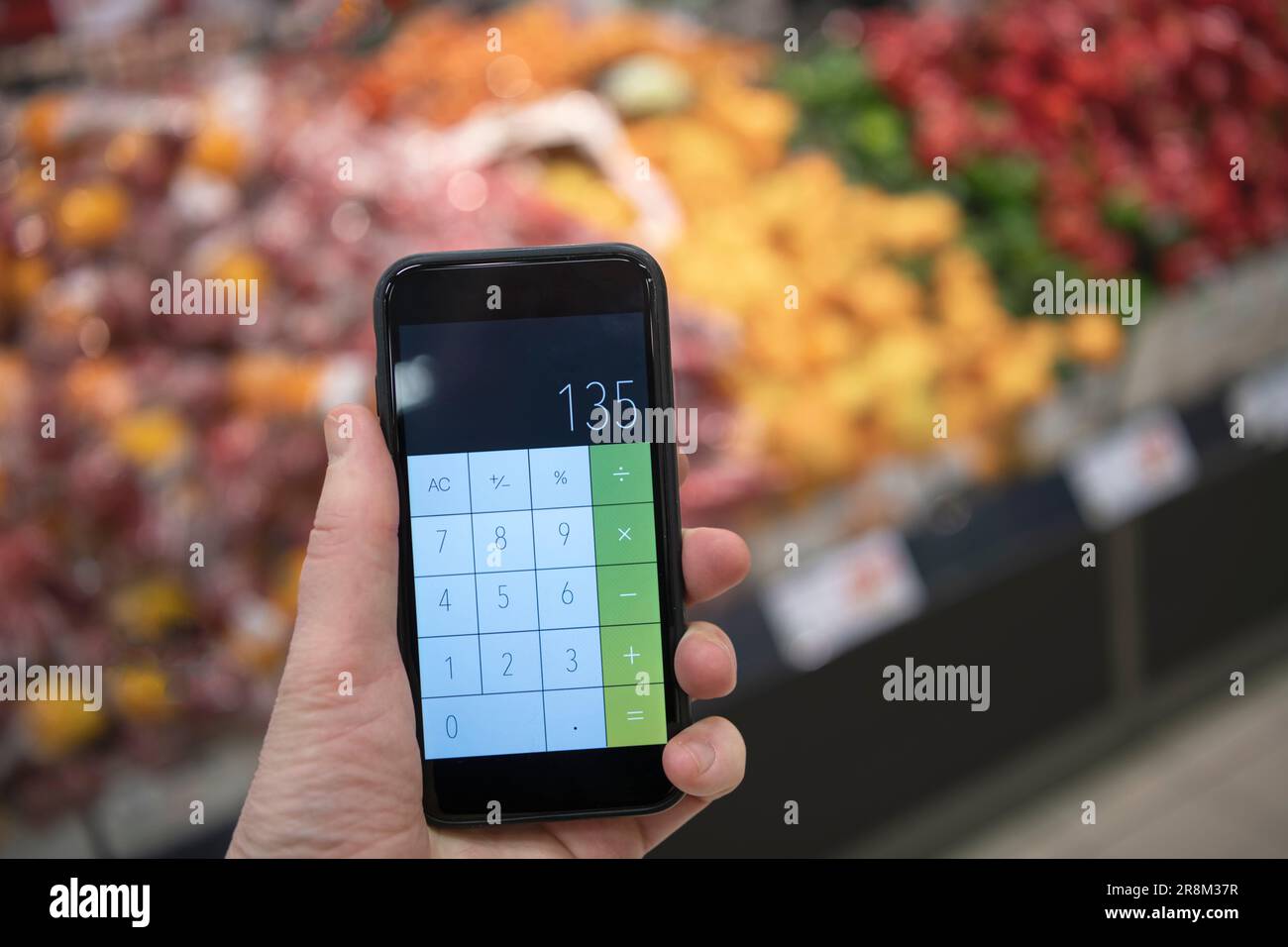 Hand holding calculator in supermarket Stock Photo - Alamy