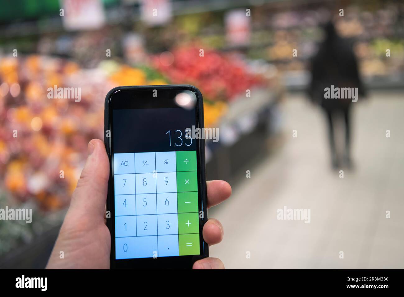 Hand holding calculator in supermarket Stock Photo - Alamy