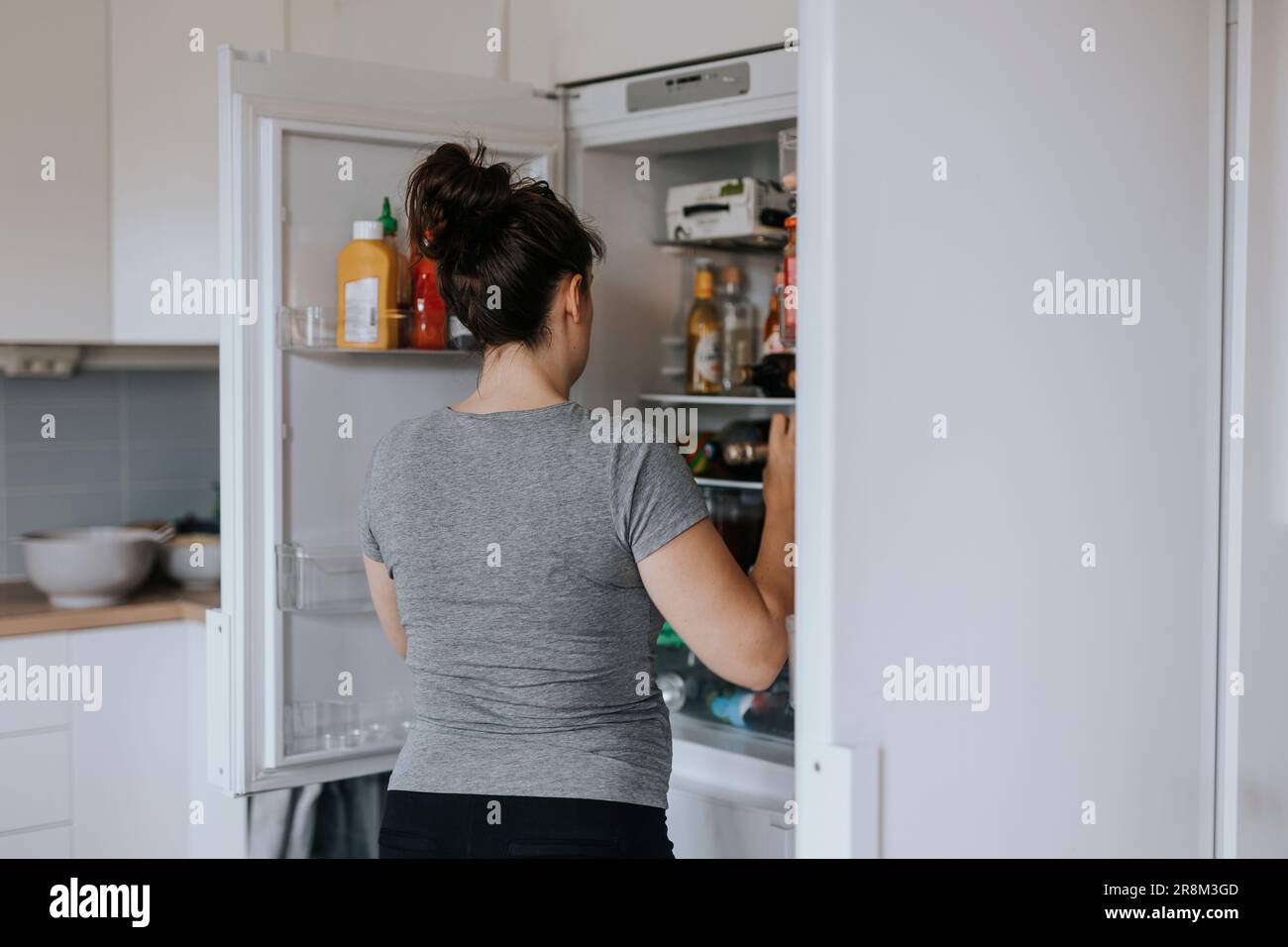 Rear view of woman standing in front of open fridge Stock Photo - Alamy