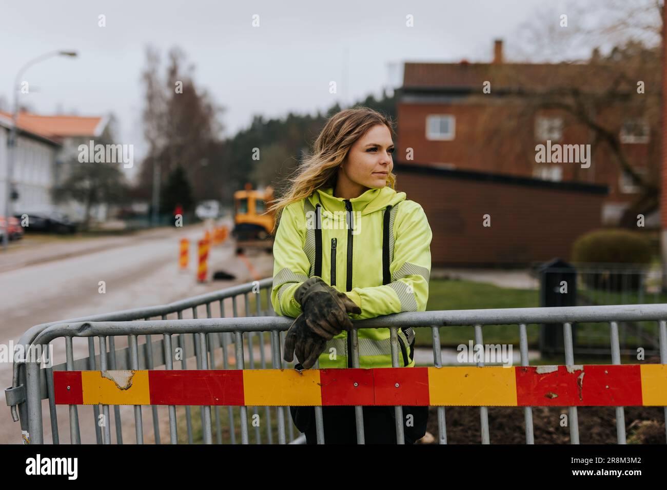 Female road worker leaning against traffic barrier Stock Photo - Alamy