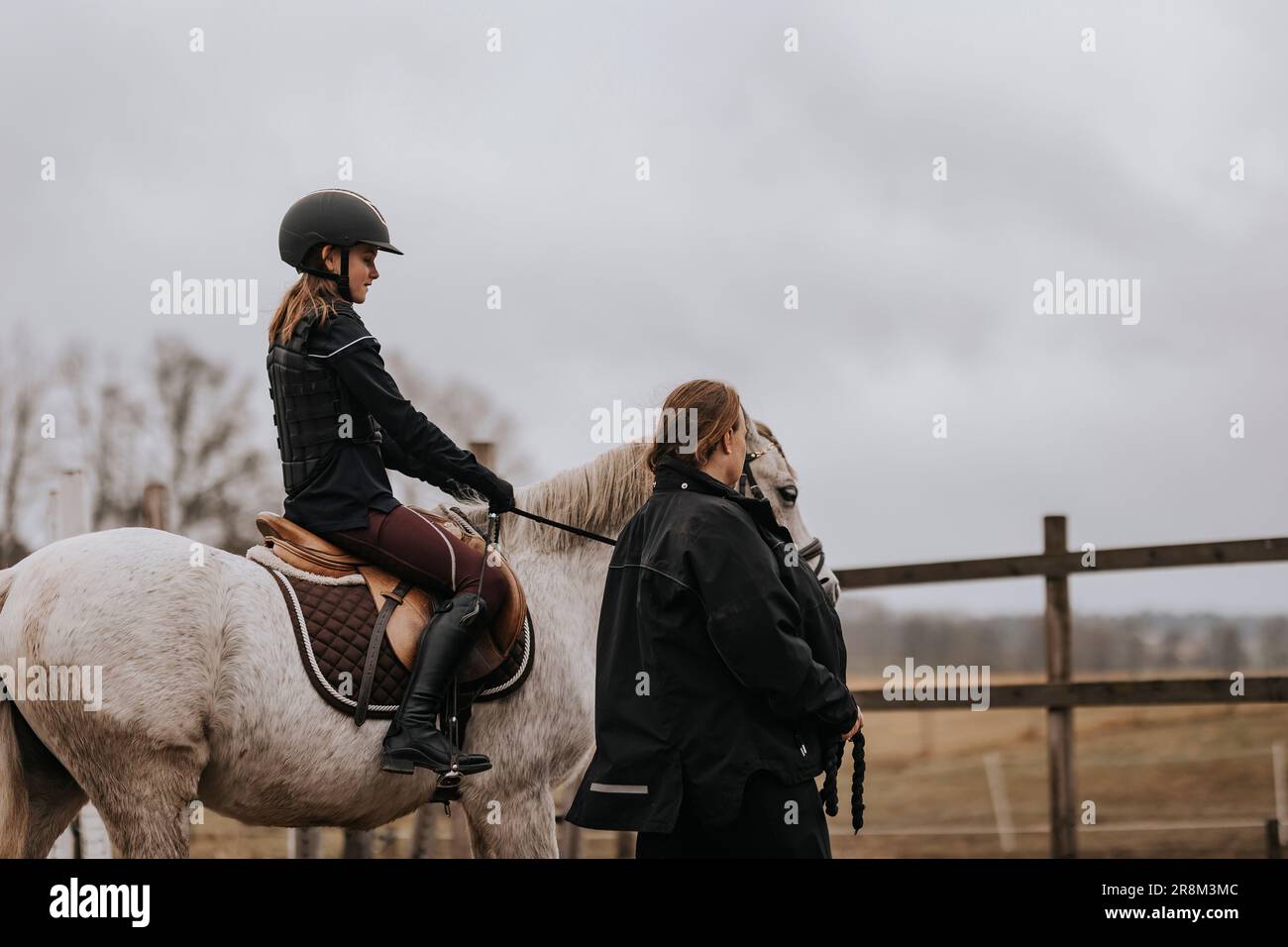 Girl horseback riding with female instructor walking along her Stock ...