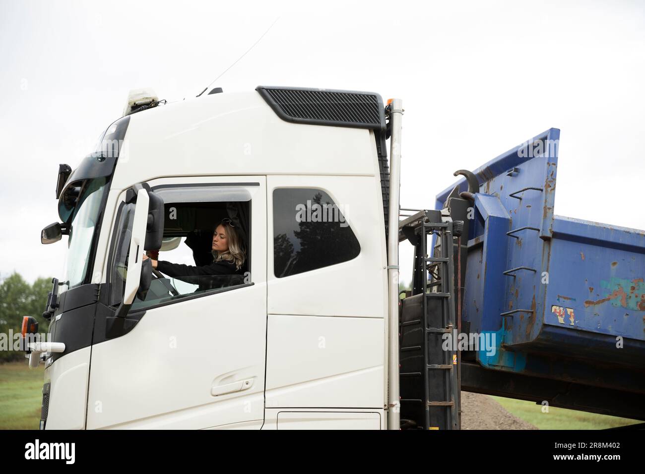 Woman driving long-distance lorry preparing to tipping off the load ...