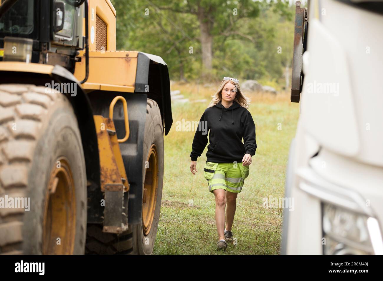 Young female construction worker walking next to excavator Stock Photo ...
