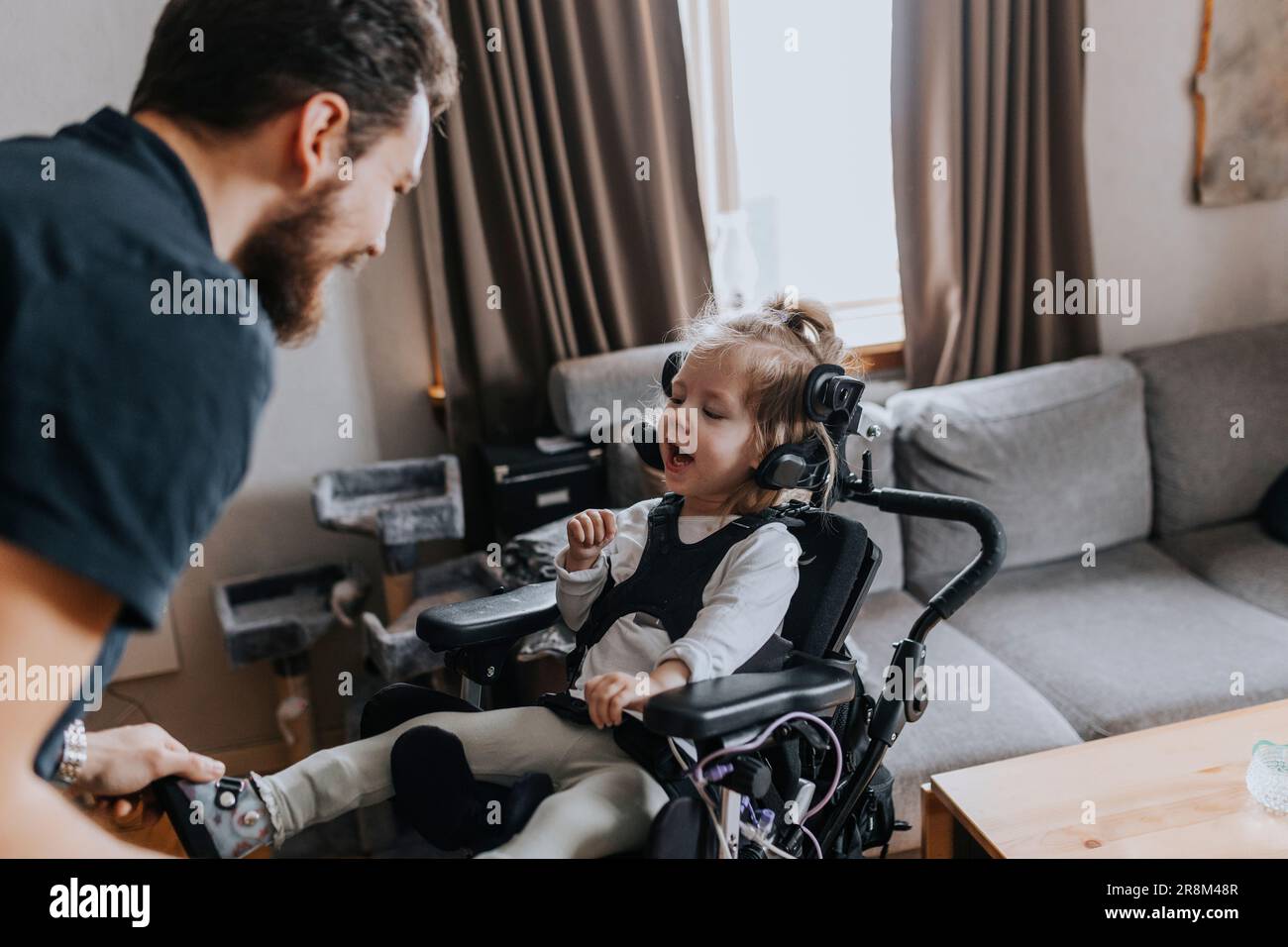 Father taking care of smiling disabled child in wheelchair Stock Photo ...