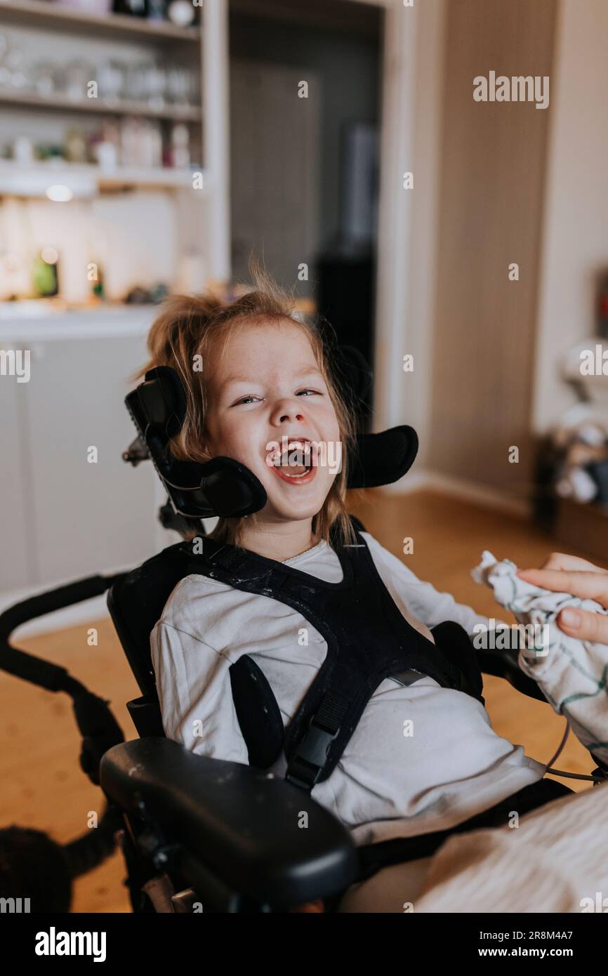 Happy disabled girl in wheelchair looking at camera Stock Photo - Alamy