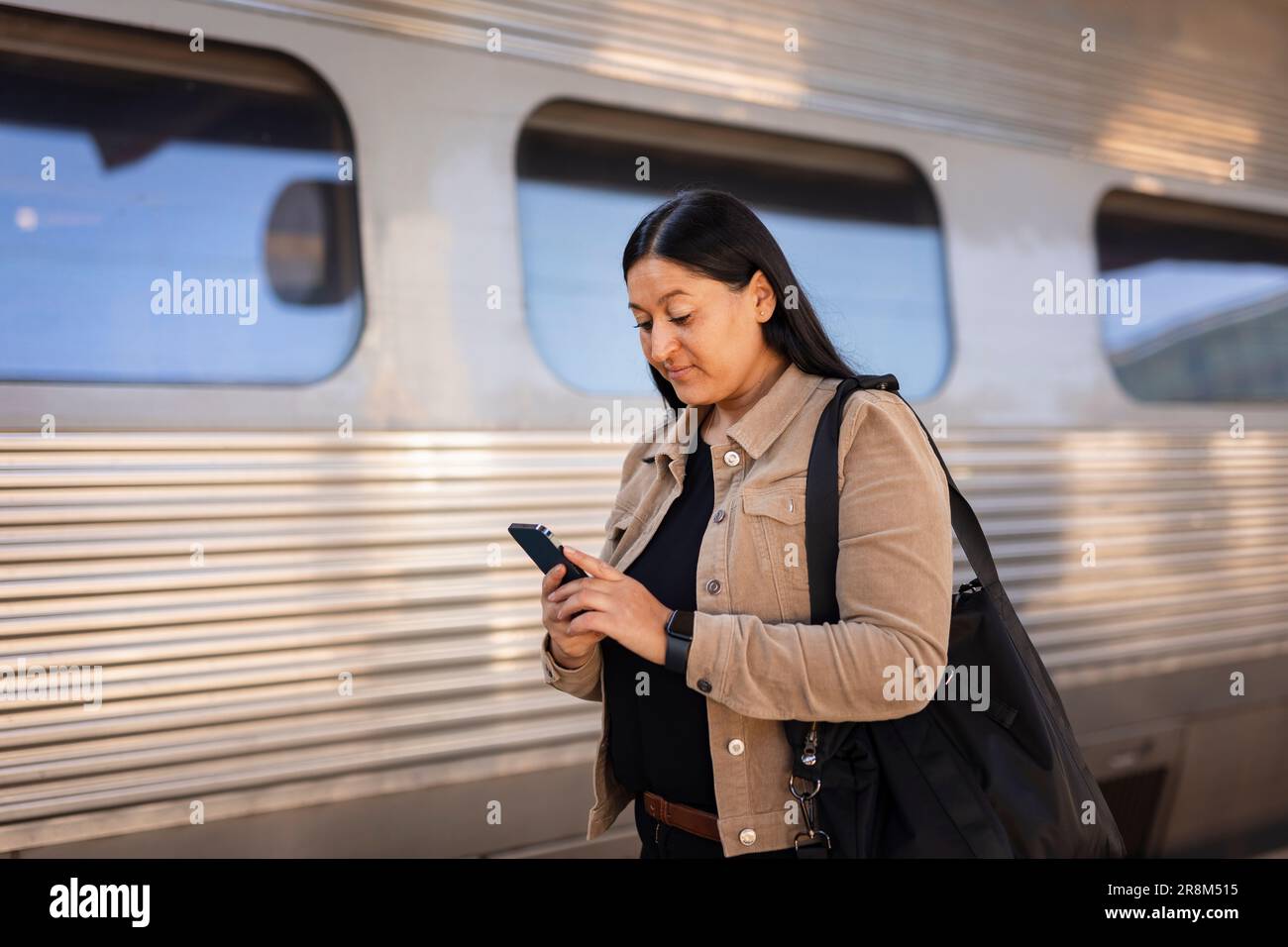 Mid adult woman at train station using cell phone Stock Photo - Alamy