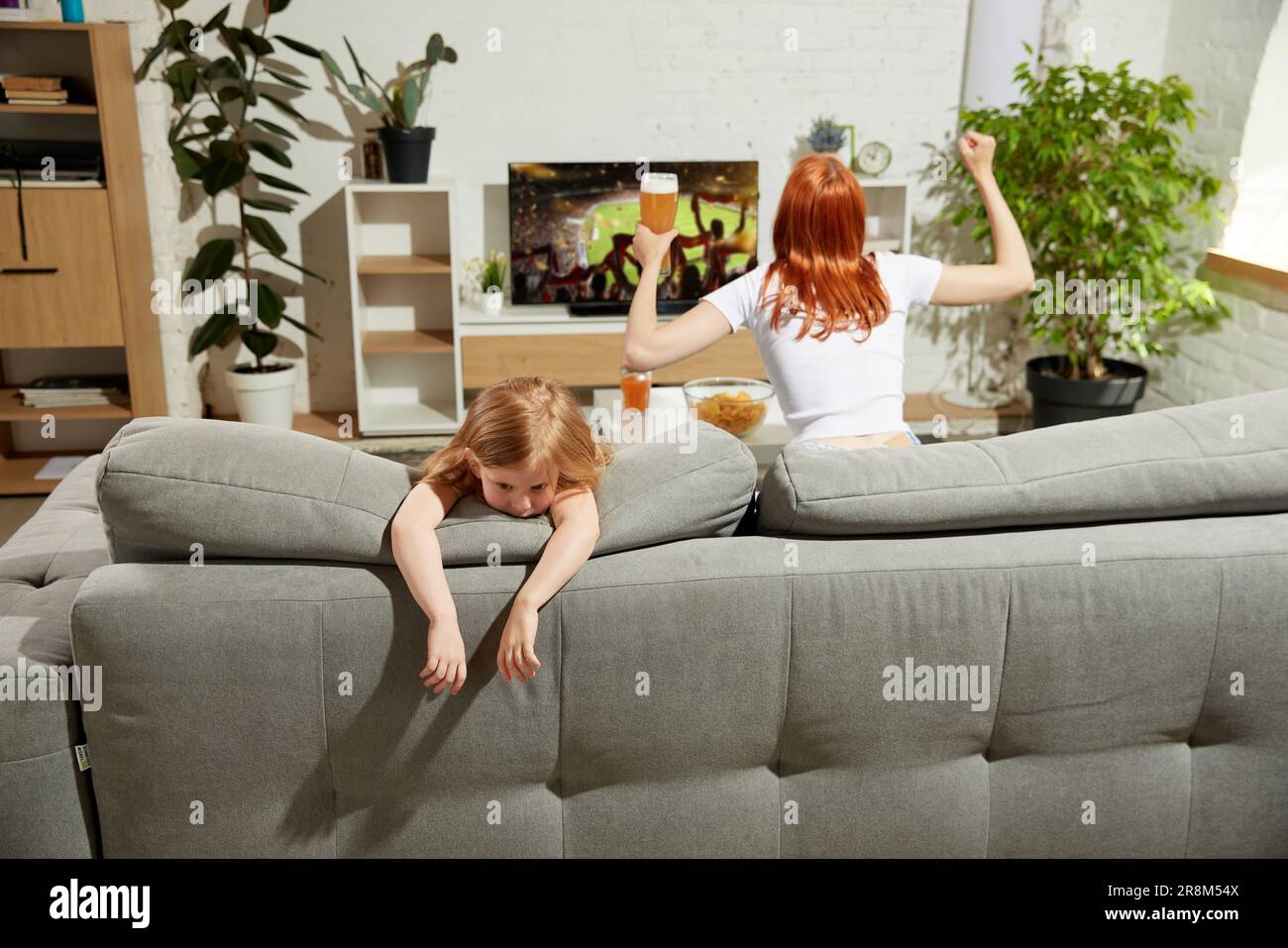 Young excited woman sitting on couch at home and emotionally watching ...