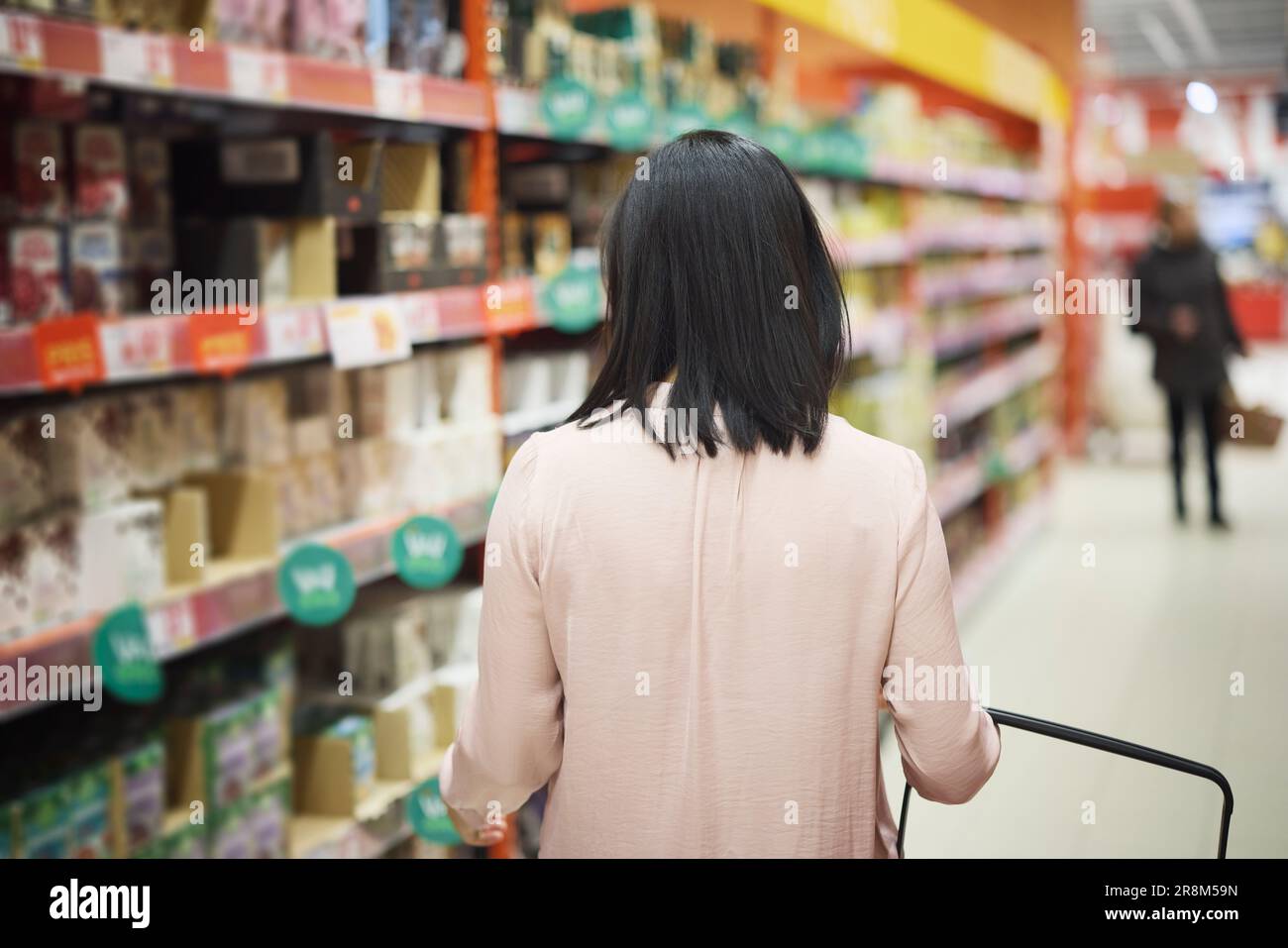 Rear view of woman looking at prices during inflation while doing ...